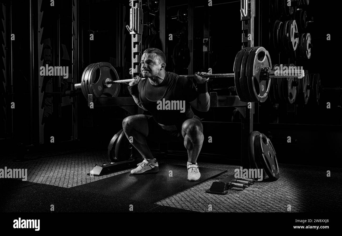 The weightlifter is getting ready to stand with a heavy barbell. Is at ...