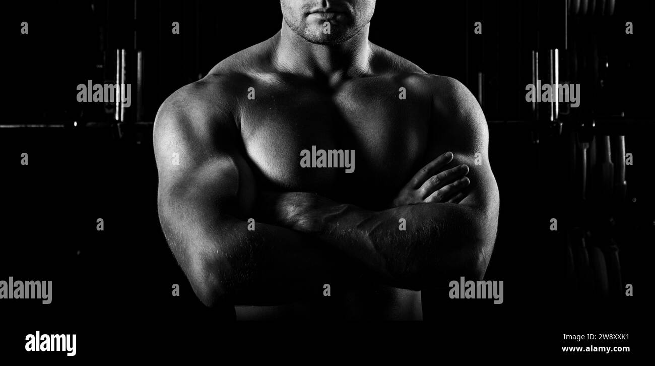 The weightlifter is posing in front of the camera with his arms crossed ...