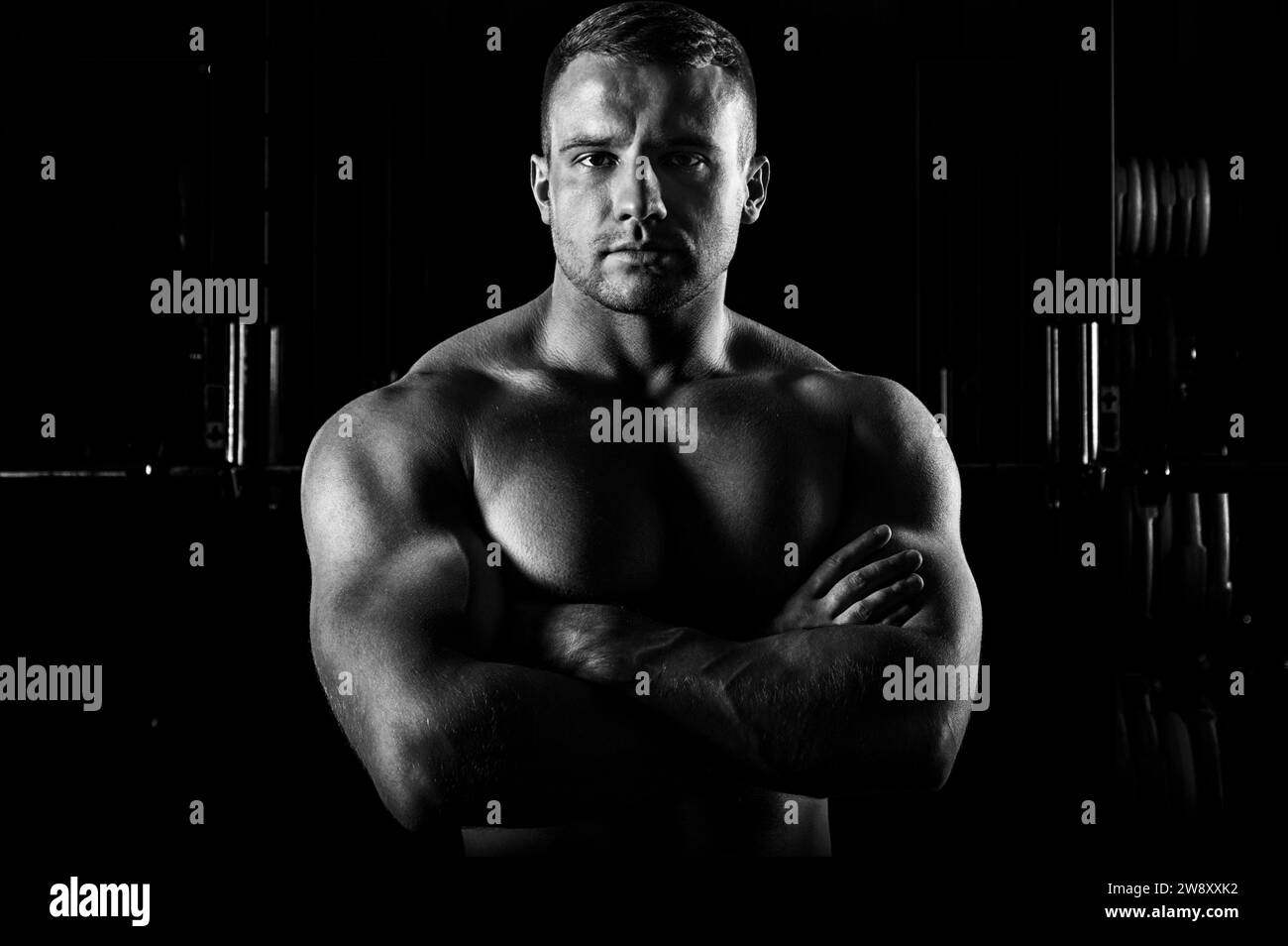 The weightlifter is posing in front of the camera with his arms crossed ...