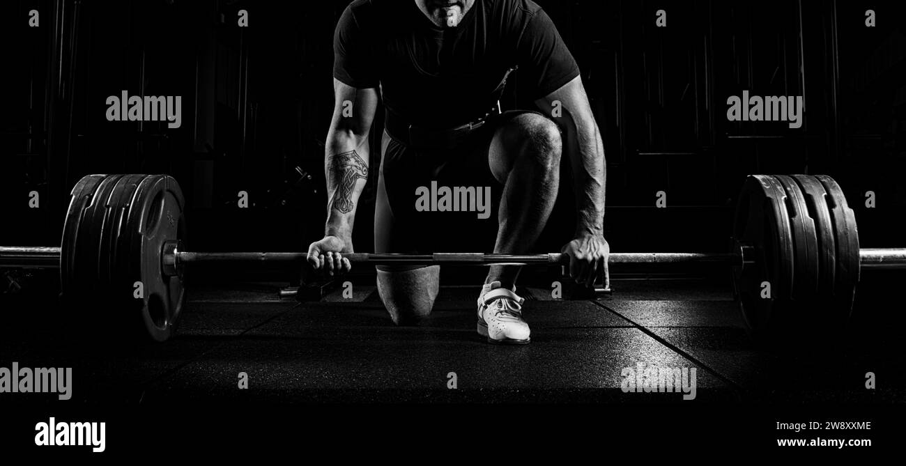 Professional athlete bent over the barbell and is preparing to lift a ...
