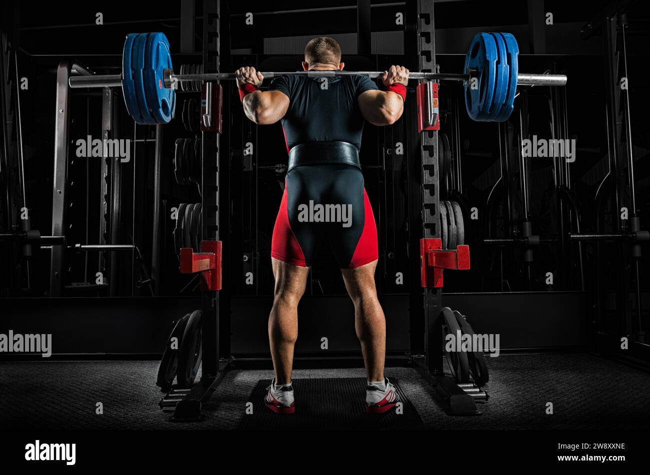 Professional athlete is standing with a barbell on his shoulders and is ...