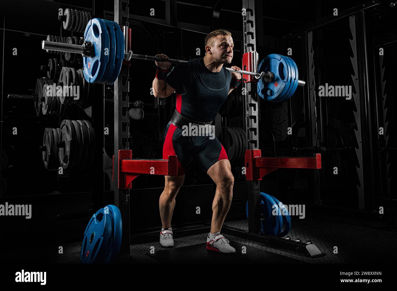 The weightlifter is preparing to lift a very heavy barbell. He exhales ...