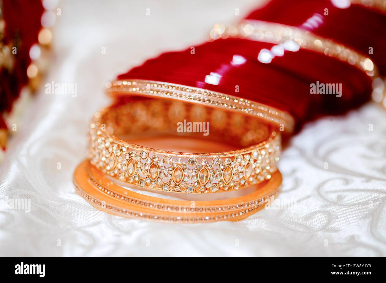 Close-up of traditional golden bangles on a red velvet background exuding luxury and elegance ...