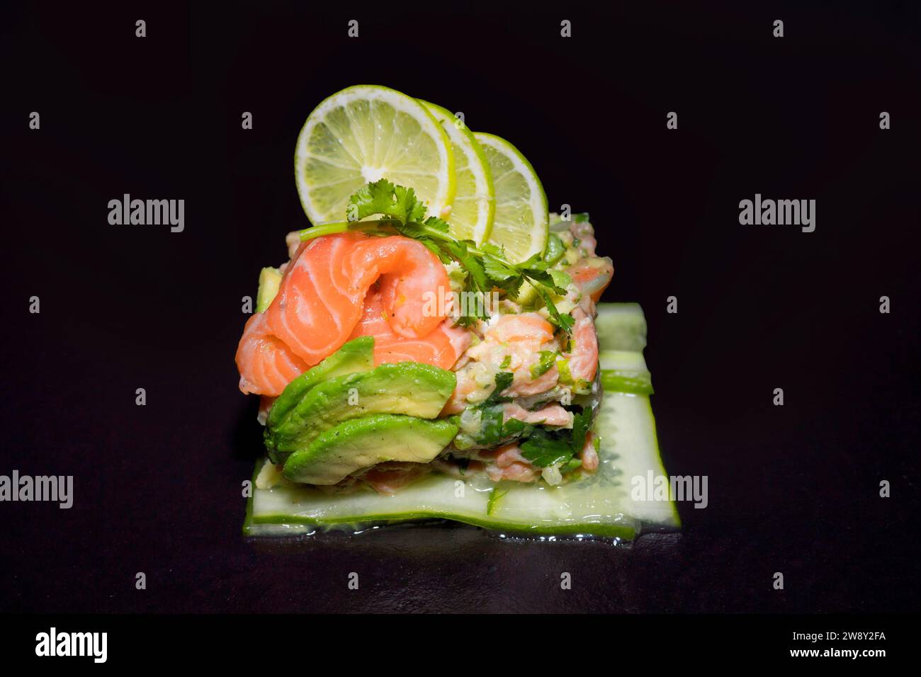 Salmon tartare on cucumber slices with fresh coriander, avocado and ...