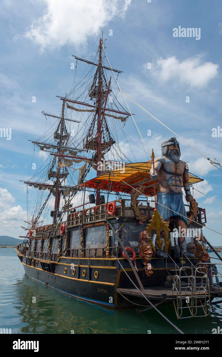 A large sailing ship with many masts and a pirate statue on board is ...