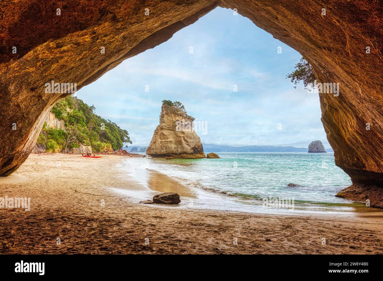View from a cave onto a beach and isolated rocks in the sea, under a ...