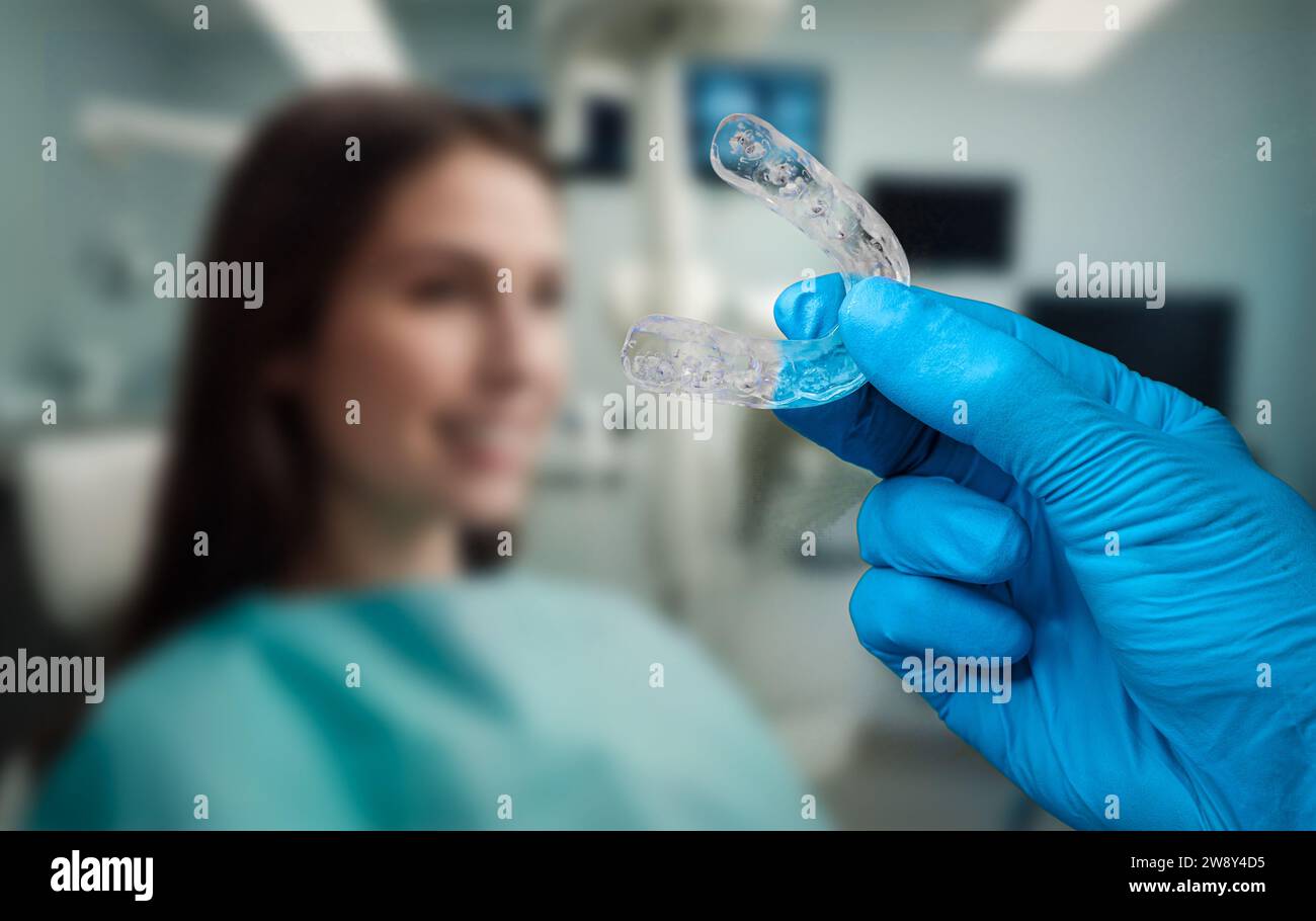 view of a doctor's hand holding a dental retainer and a blurred ...