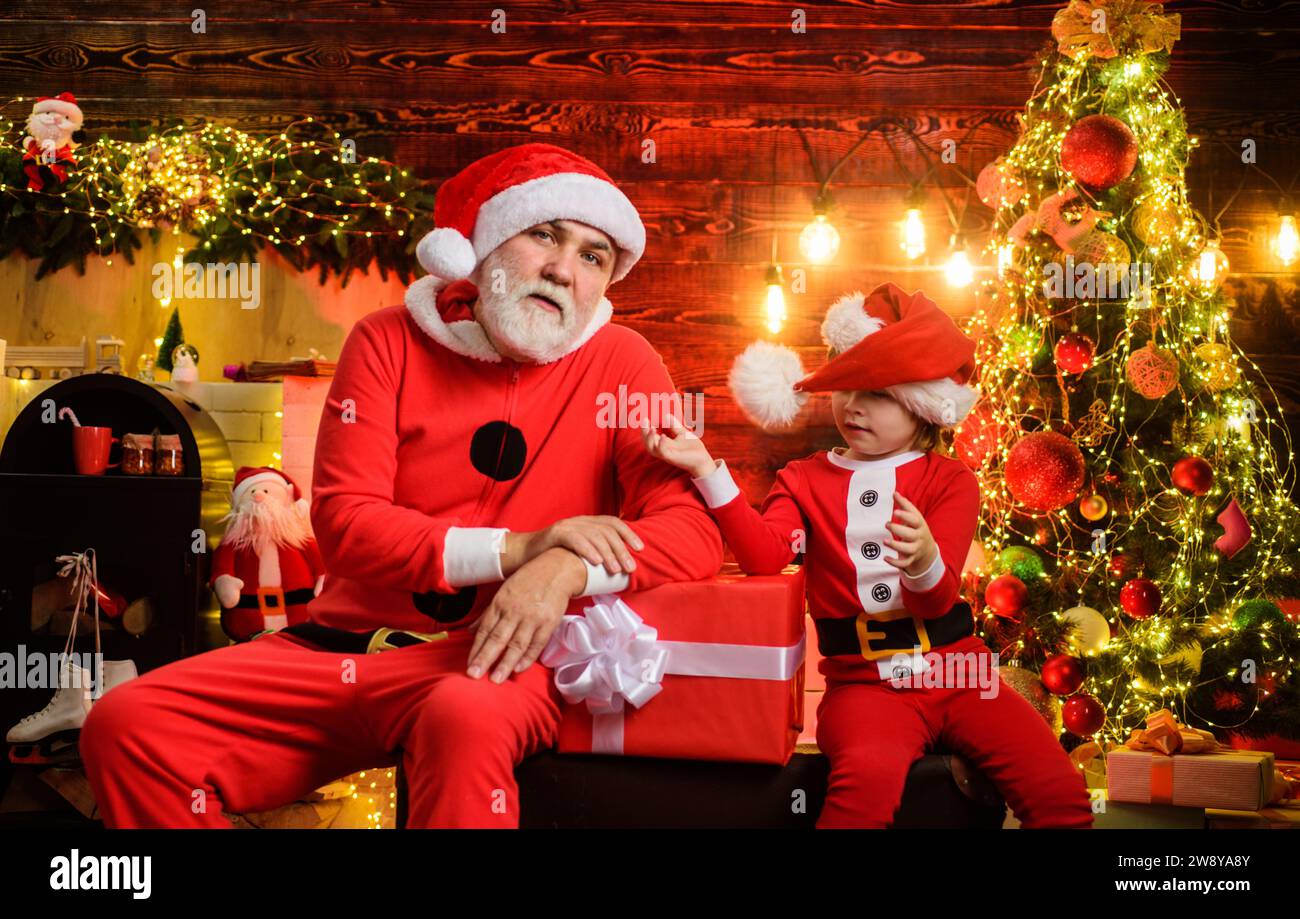 Happy holidays. Santa Claus with little helper at home near Christmas ...
