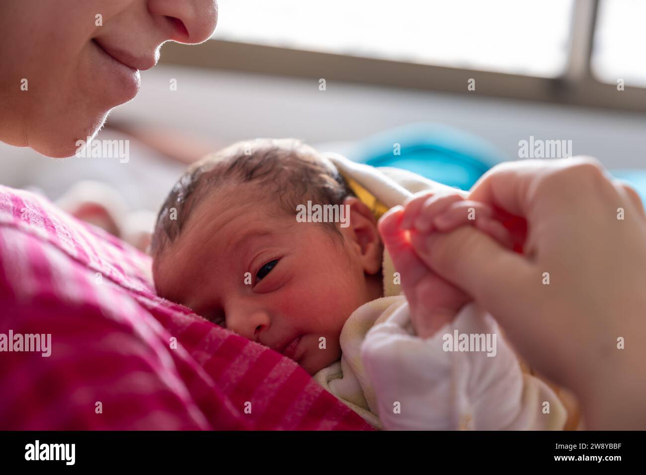 mother cuddling her newborn with smile on their faces and adorable look ...