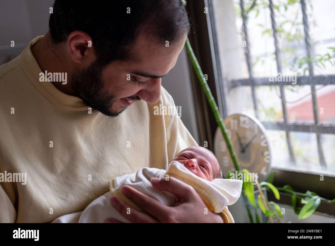 Father holding his newborn son with cheerful reaction and smile on his ...