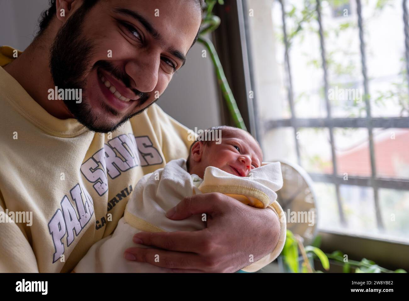 Father holding his newborn son with cheerful reaction and smile on his ...