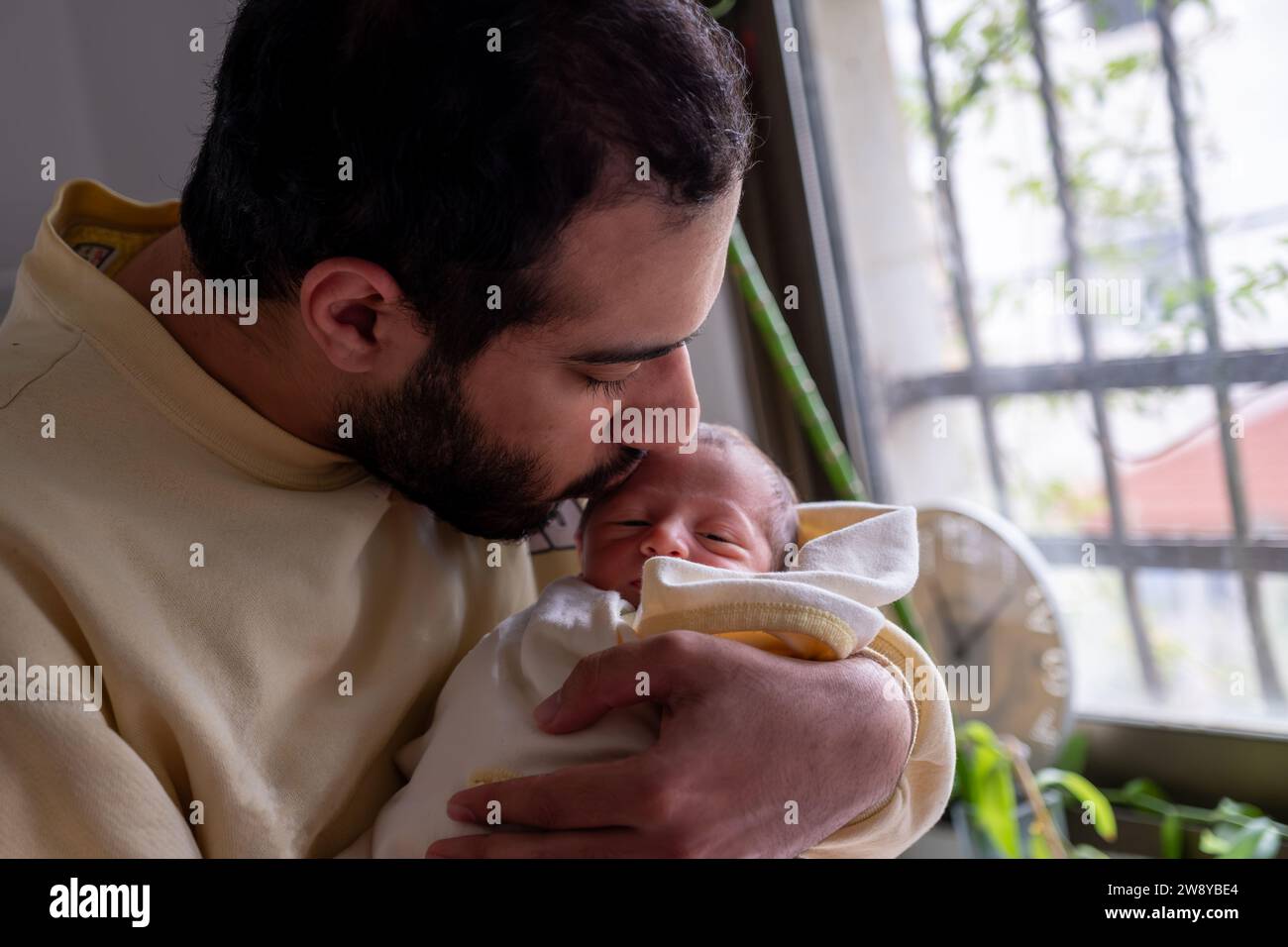 Father holding his newborn son with cheerful reaction and smile on his ...