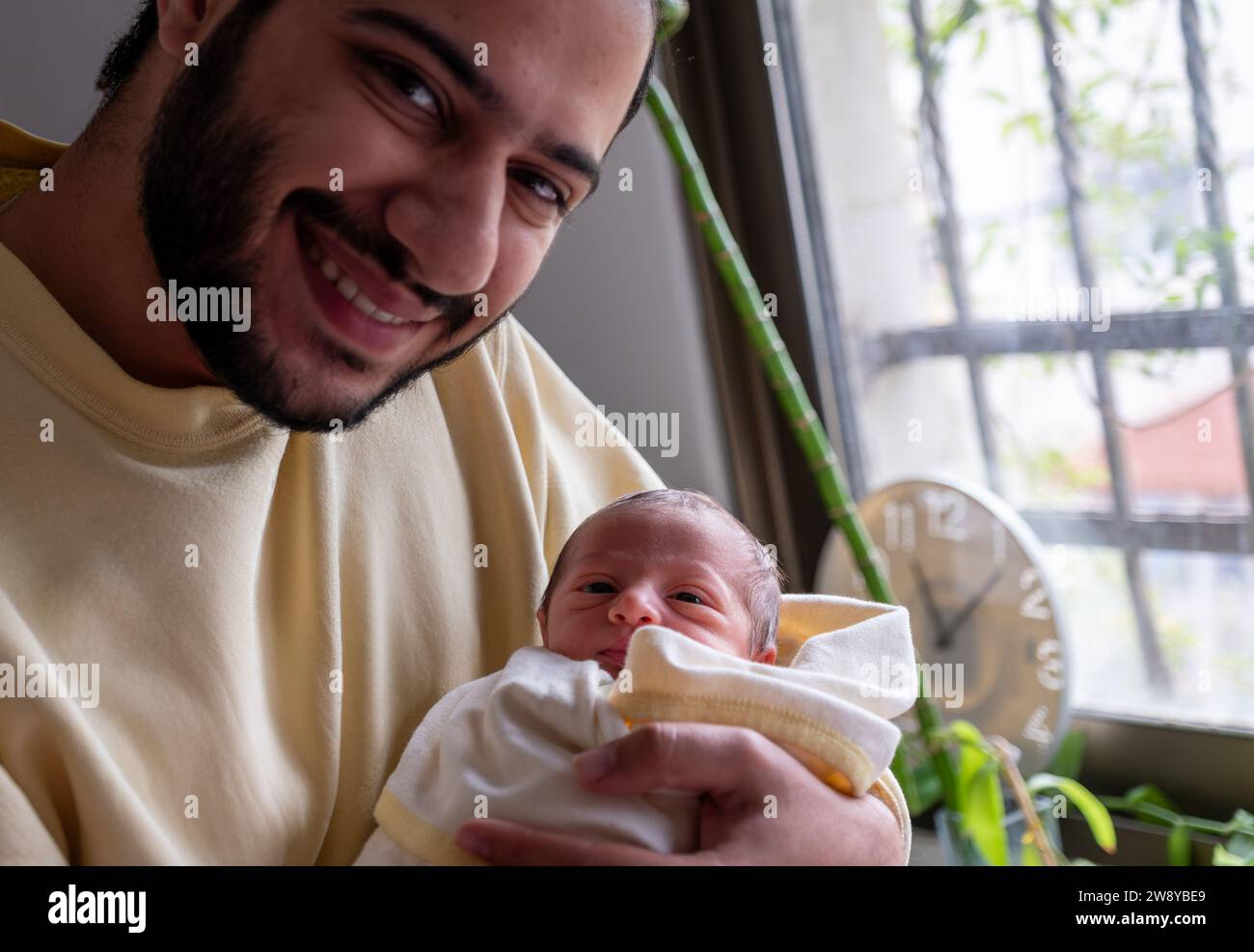 Father holding his newborn son with cheerful reaction and smile on his ...