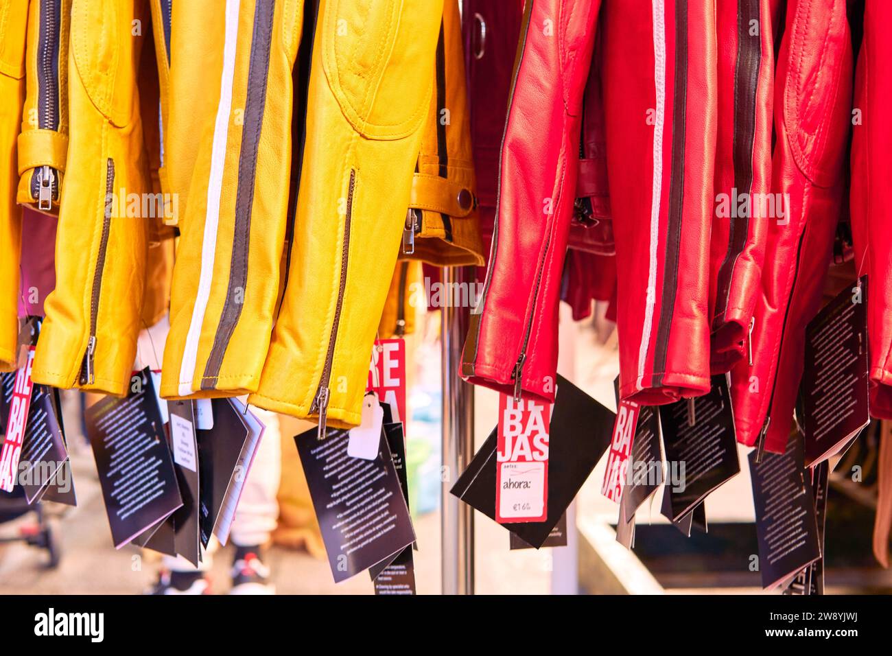 Yellow and red jackets with sale discount labels hanging from a rack on ...