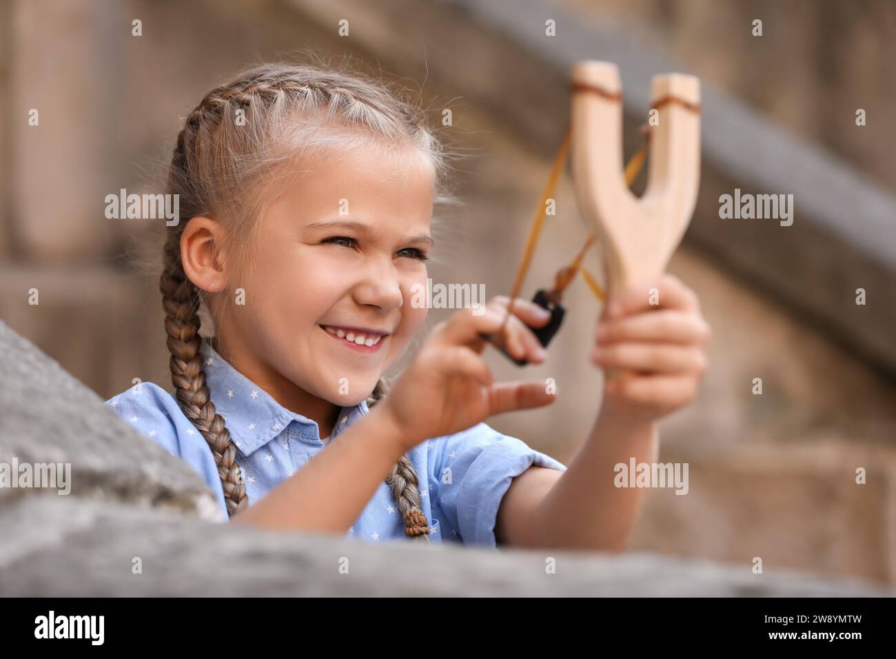 Cute little girl playing with slingshot outdoors Stock Photo - Alamy