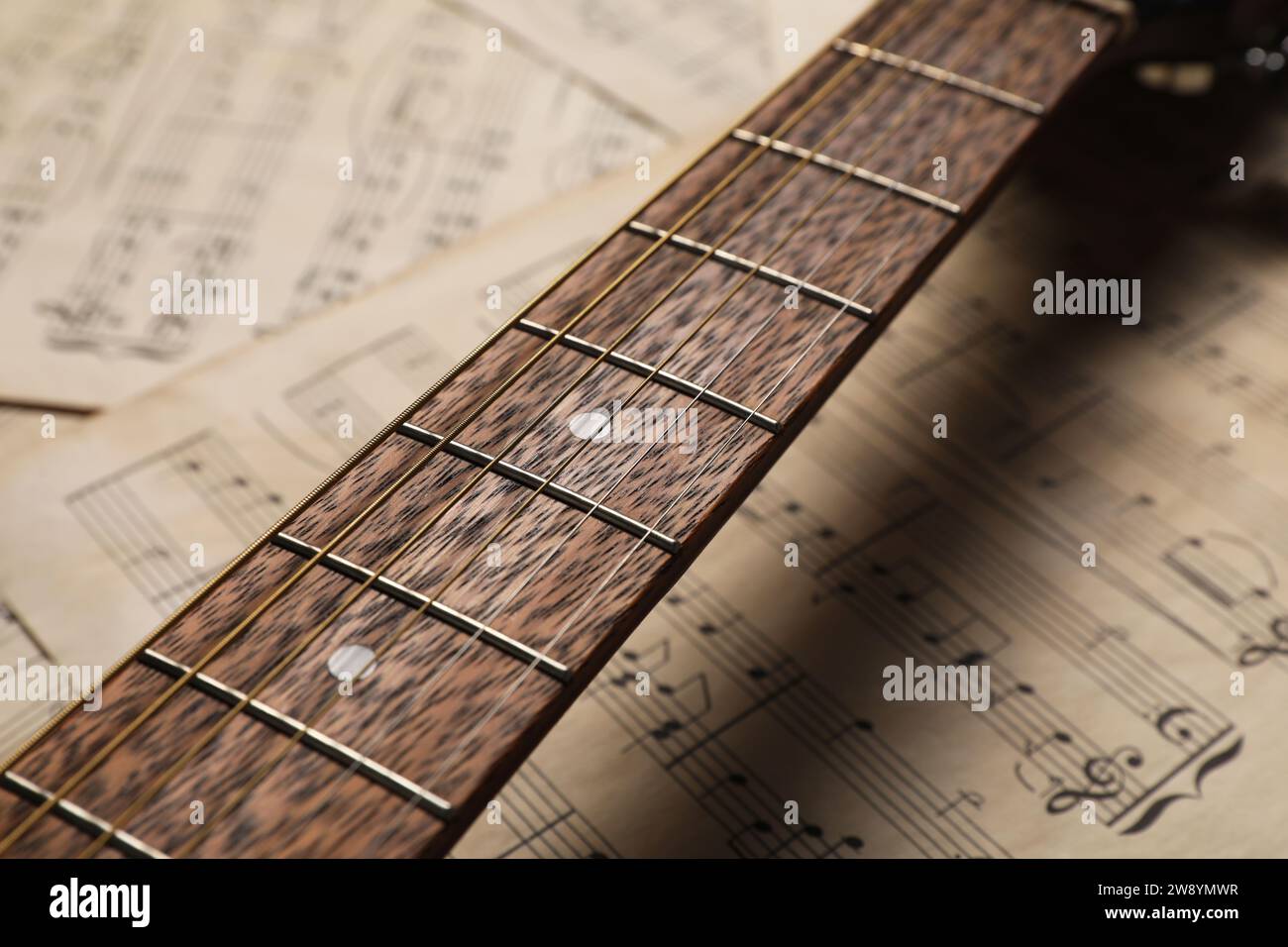 Guitar neck on paper sheets with music notes, closeup Stock Photo - Alamy