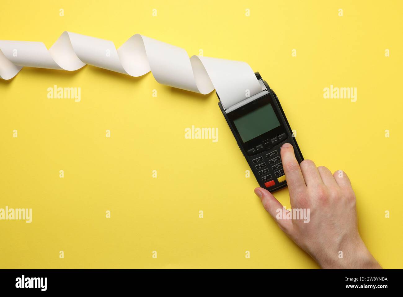Man using payment terminal with thermal paper for receipt on yellow ...