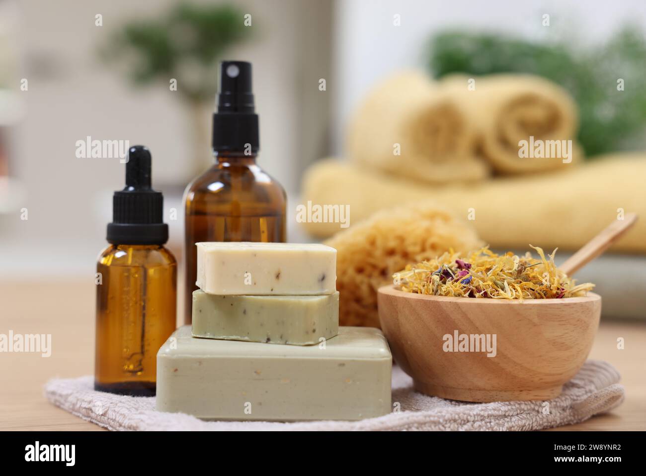 Bottles of essential oils, bowl with dry flowers, soap bars and natural ...