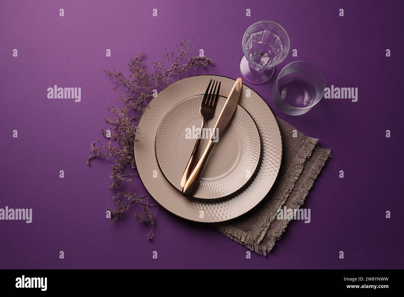 Stylish table setting. Plates, cutlery, glasses and floral decor on ...