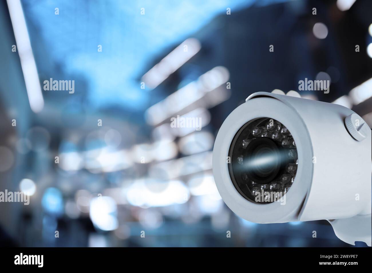 Modern security CCTV camera against blurred background, space for text ...