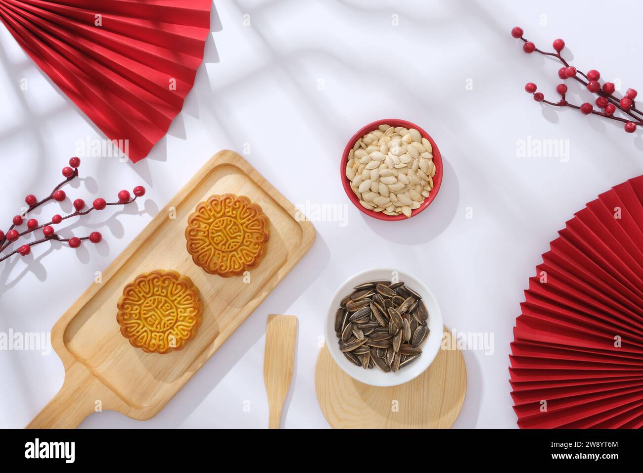Delicious mooncakes, dry seeds and red decorations displayed on white ...