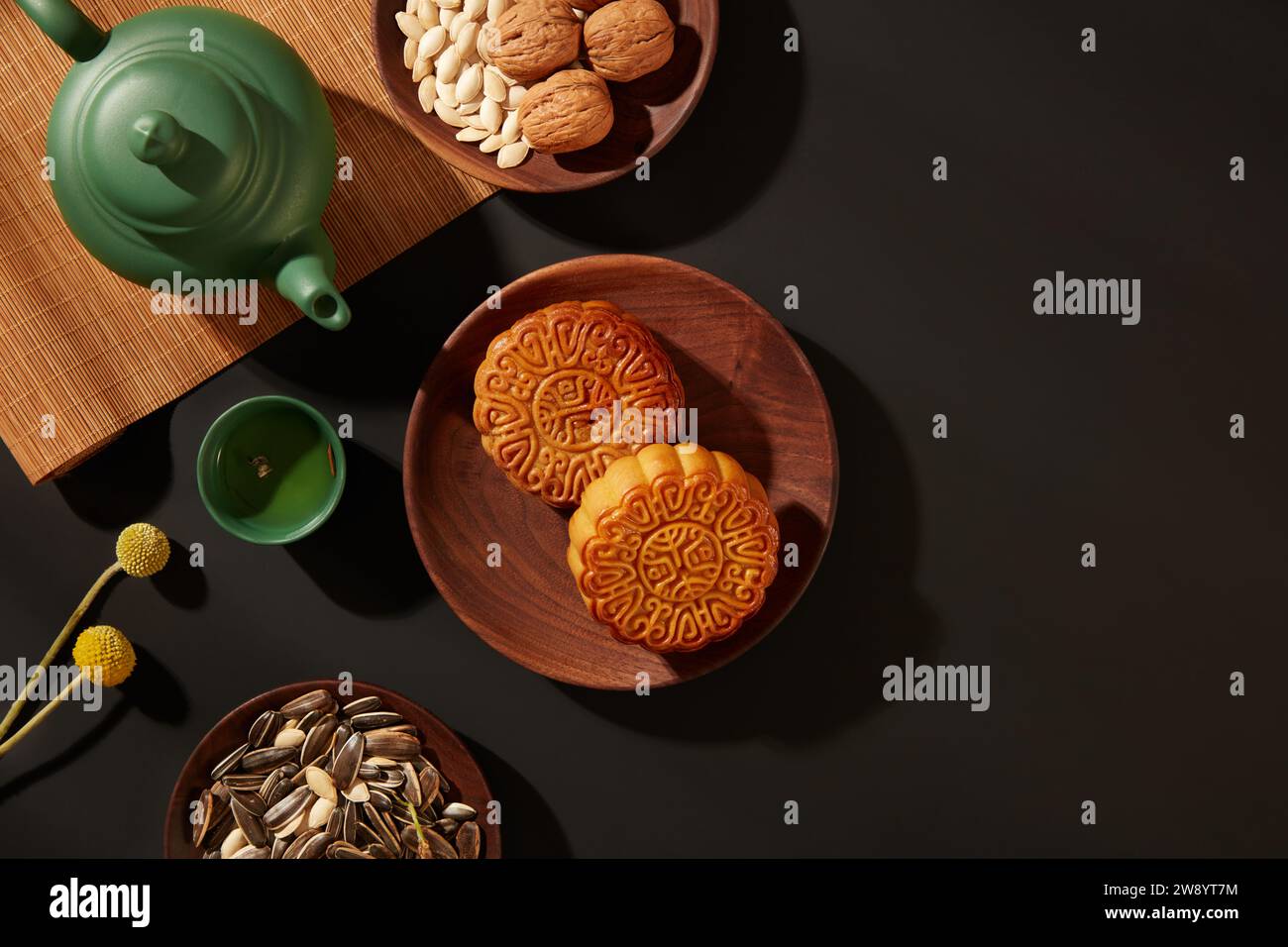 Delicious mooncakes, set of tea and dry nuts on black background. Mid ...