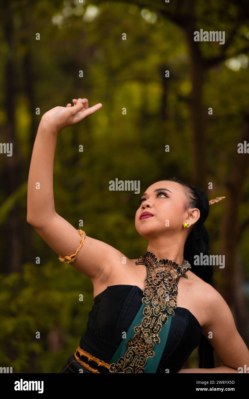 Balinese women raise their hands in the air while dancing in green ...