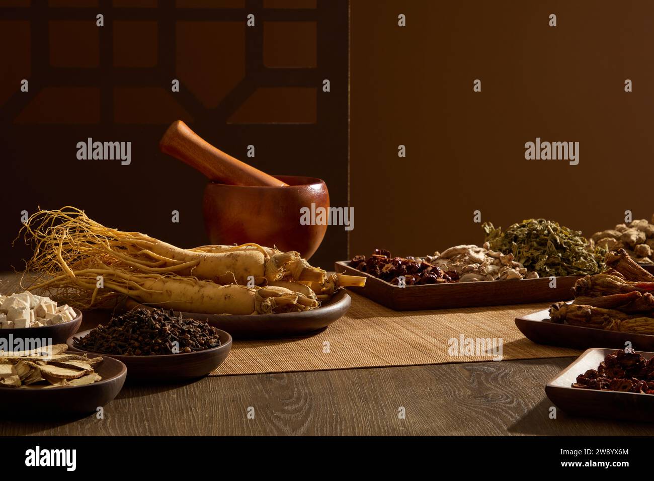 Front view of traditional herbs on wooden trays, mortar and pestle on ...
