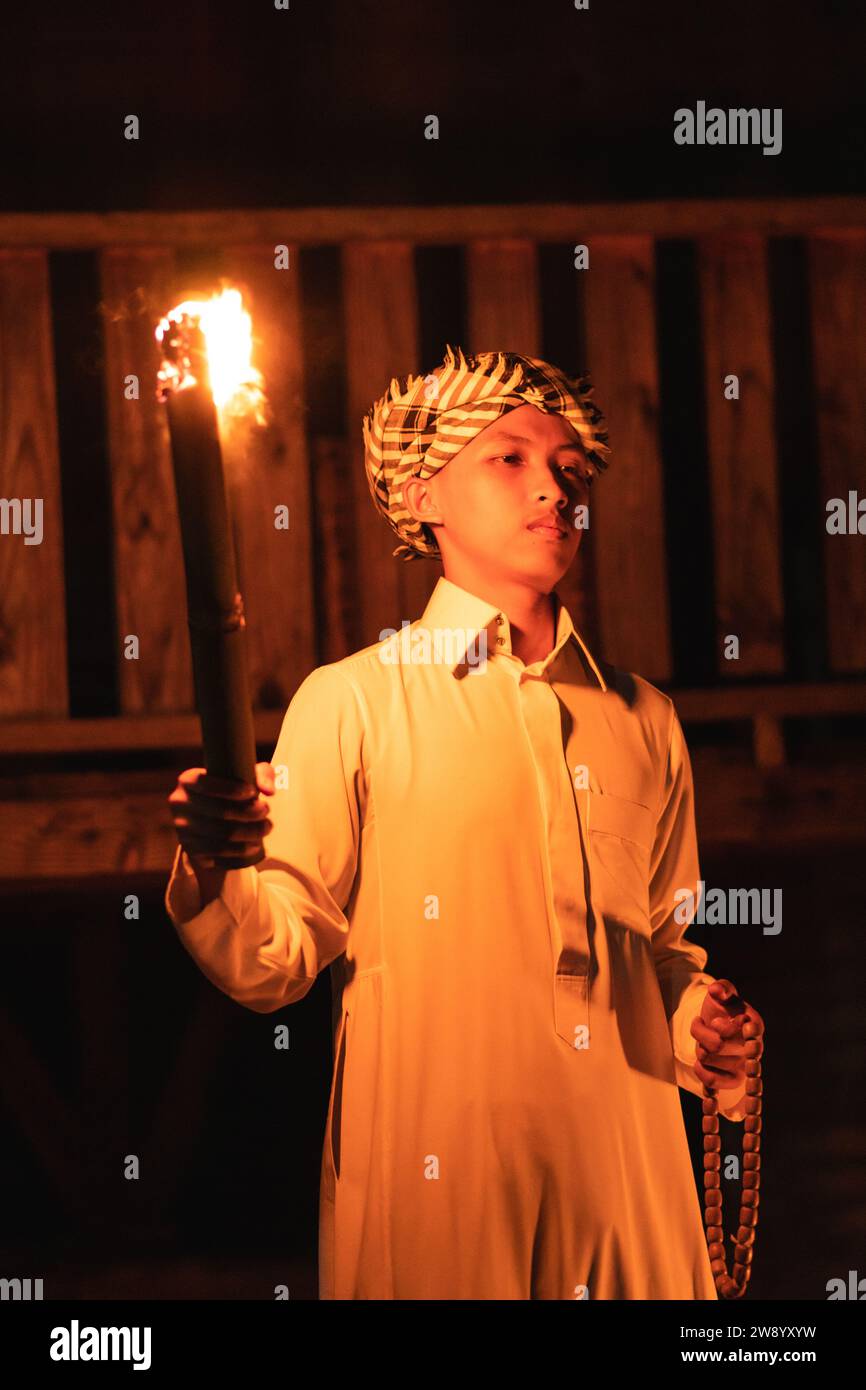 An Arabian man holding a fire torch in the front of a wooden house in ...
