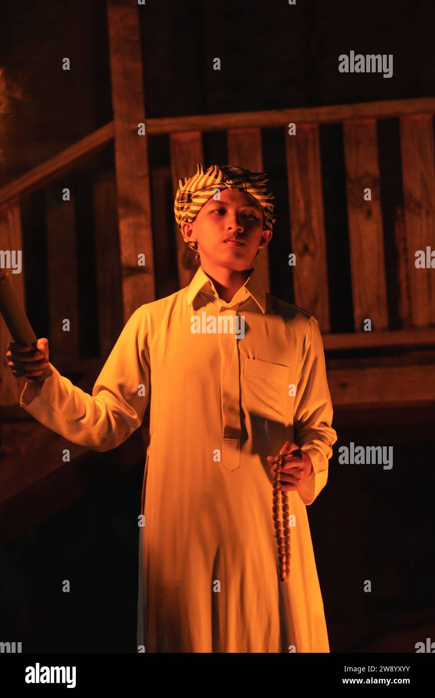 An Arabian man holding a fire torch in the front of a wooden house in ...