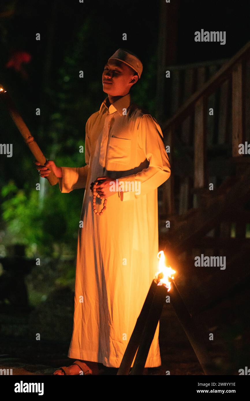 A Muslim man standing with the fire torch in her hand at the front of ...