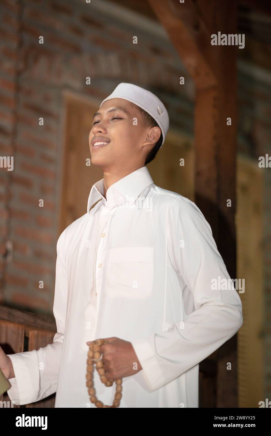 A Muslim man standing on the stairs in front of the traditional house ...