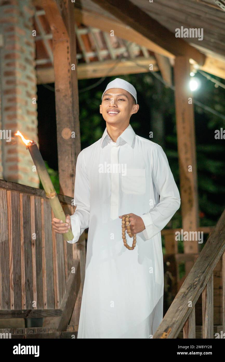A Muslim man standing on the stairs in front of the traditional house ...