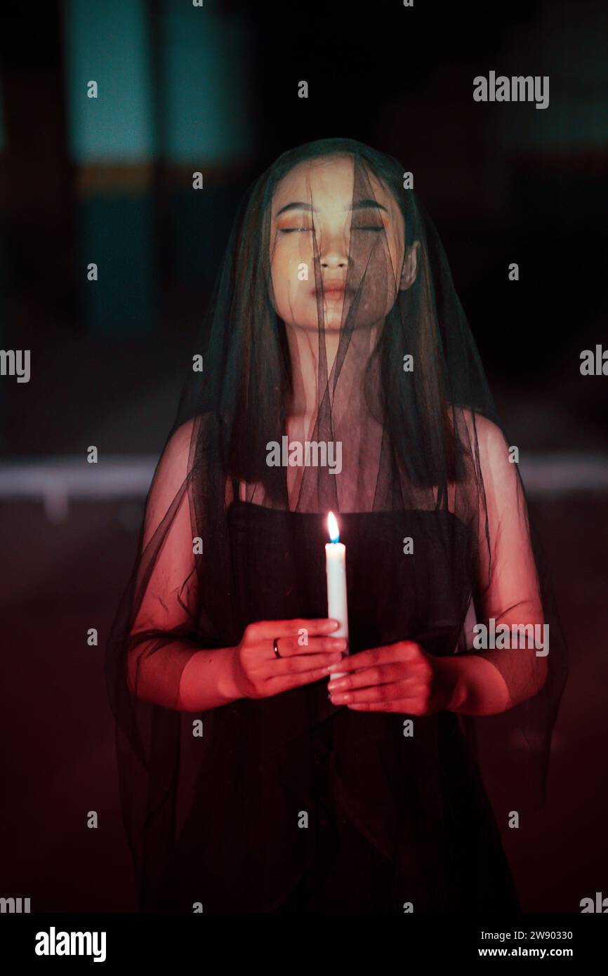 a female devil worshiper with a transparent veil is performing a spooky ...