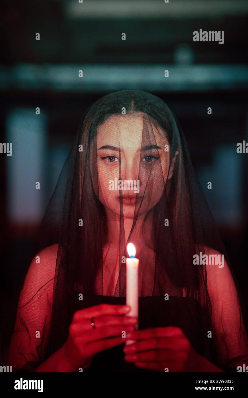 a female devil worshiper with a transparent veil is performing a spooky ...