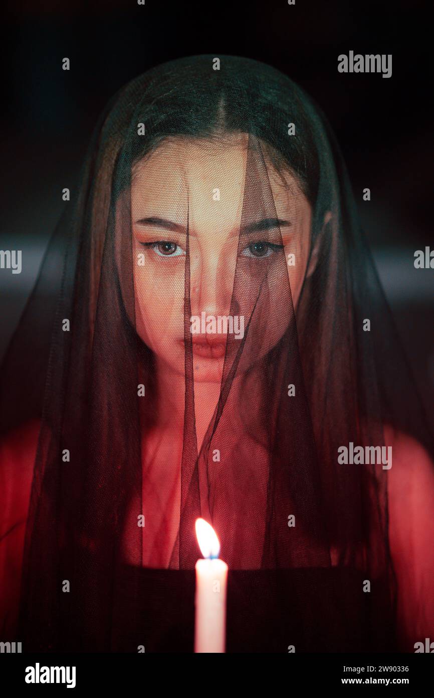 a female devil worshiper with a transparent veil is performing a spooky ...