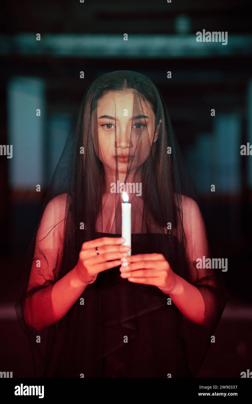 a female devil worshiper with a transparent veil is performing a spooky ...