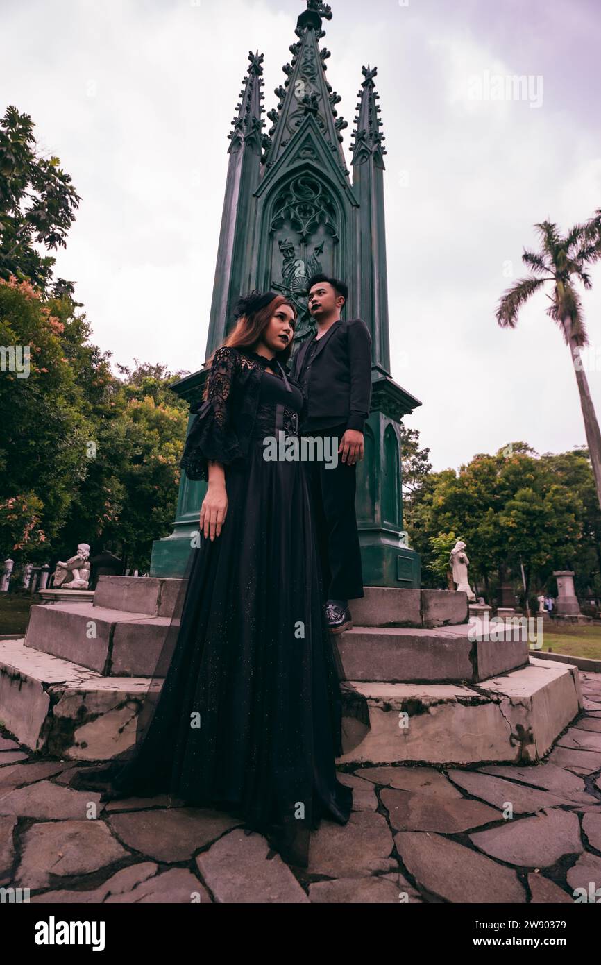 a pair of Asian teenagers standing in front of the funeral monument and ...