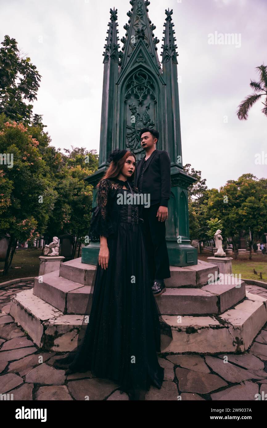 a pair of Asian teenagers standing in front of the funeral monument and ...