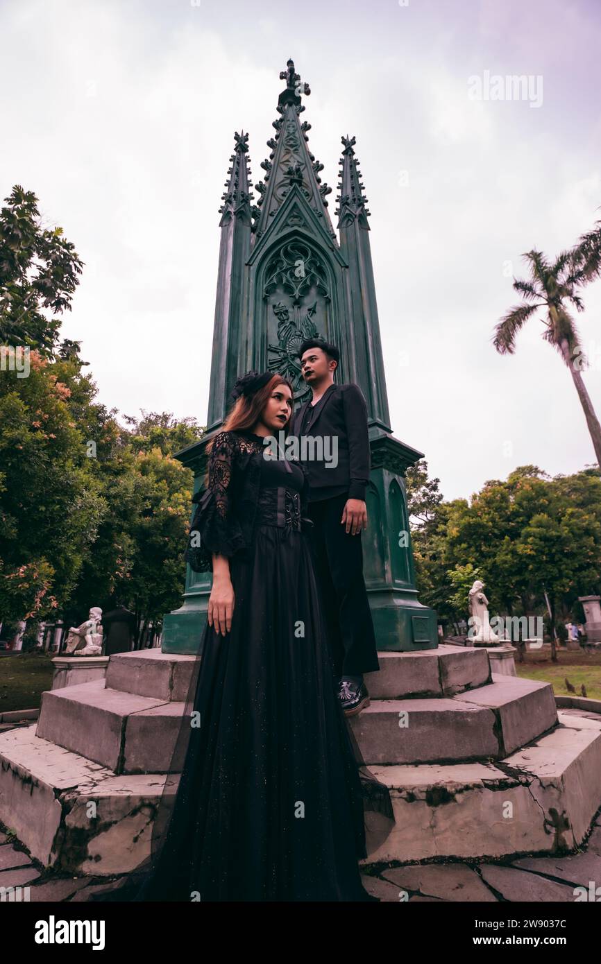 a pair of Asian teenagers standing in front of the funeral monument and ...