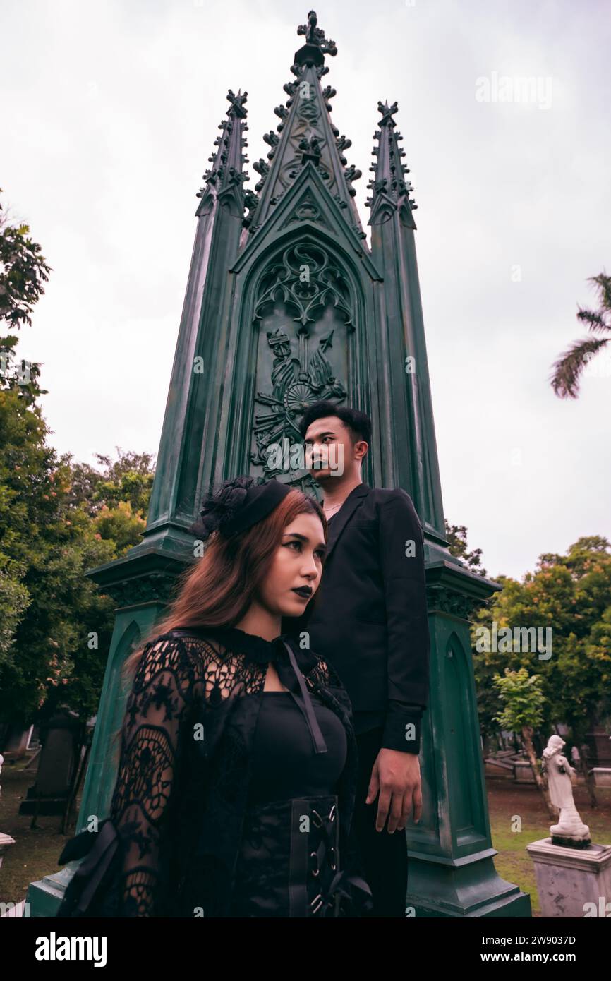 a pair of Asian teenagers standing in front of the funeral monument and ...