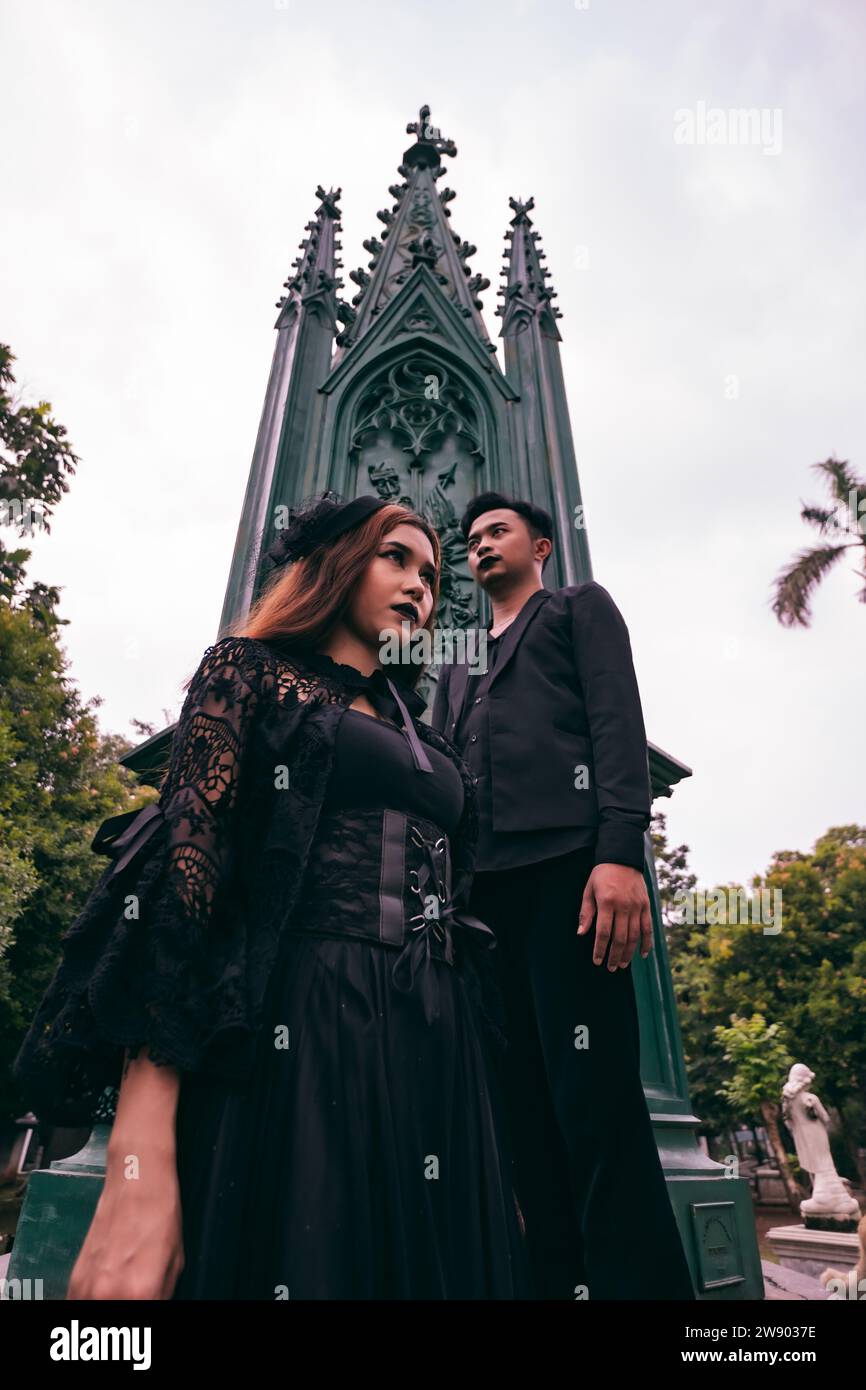 a pair of Asian teenagers standing in front of the funeral monument and ...