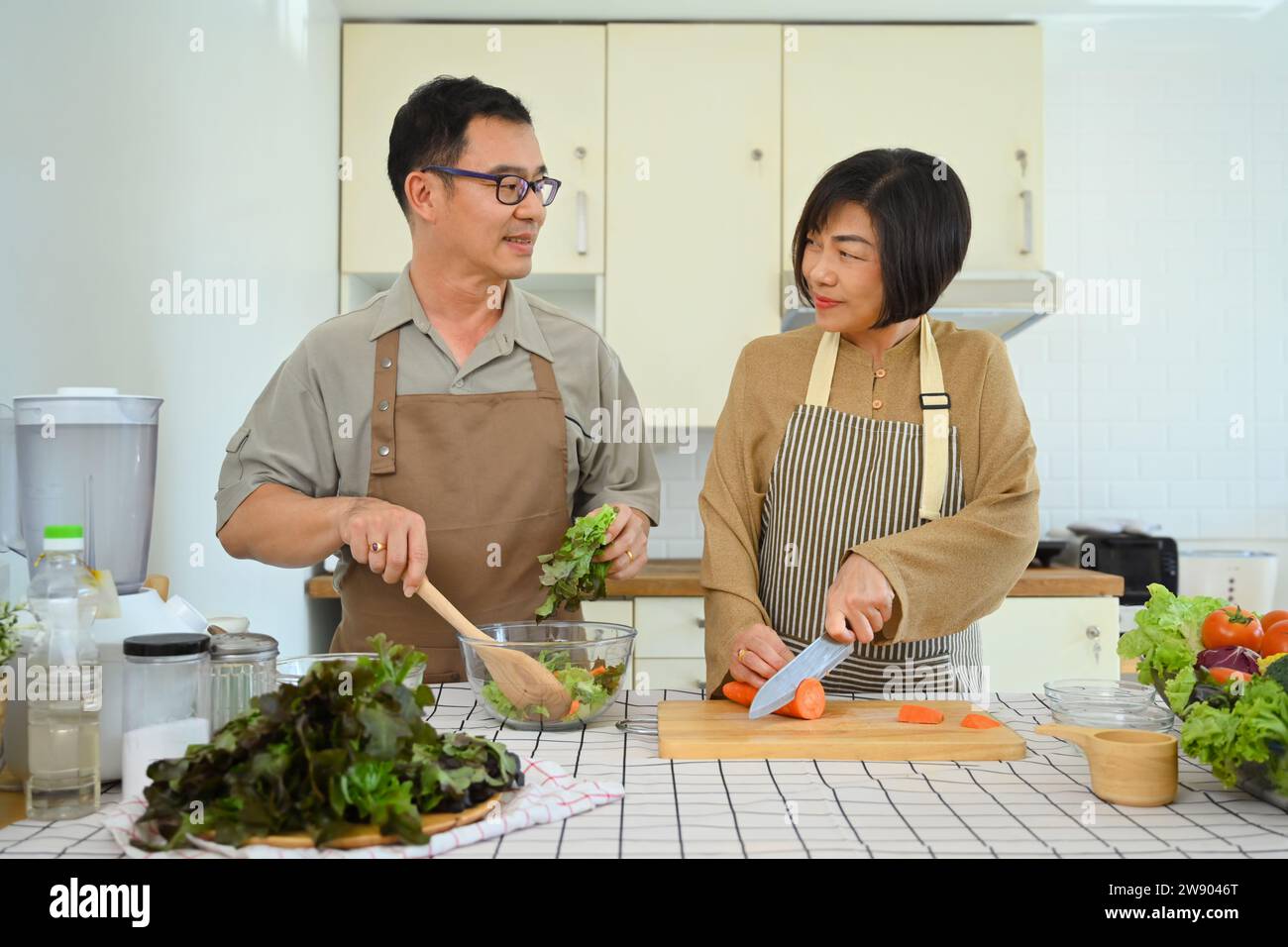 Happy senior couple having conversation, making healthy vegan meal ...