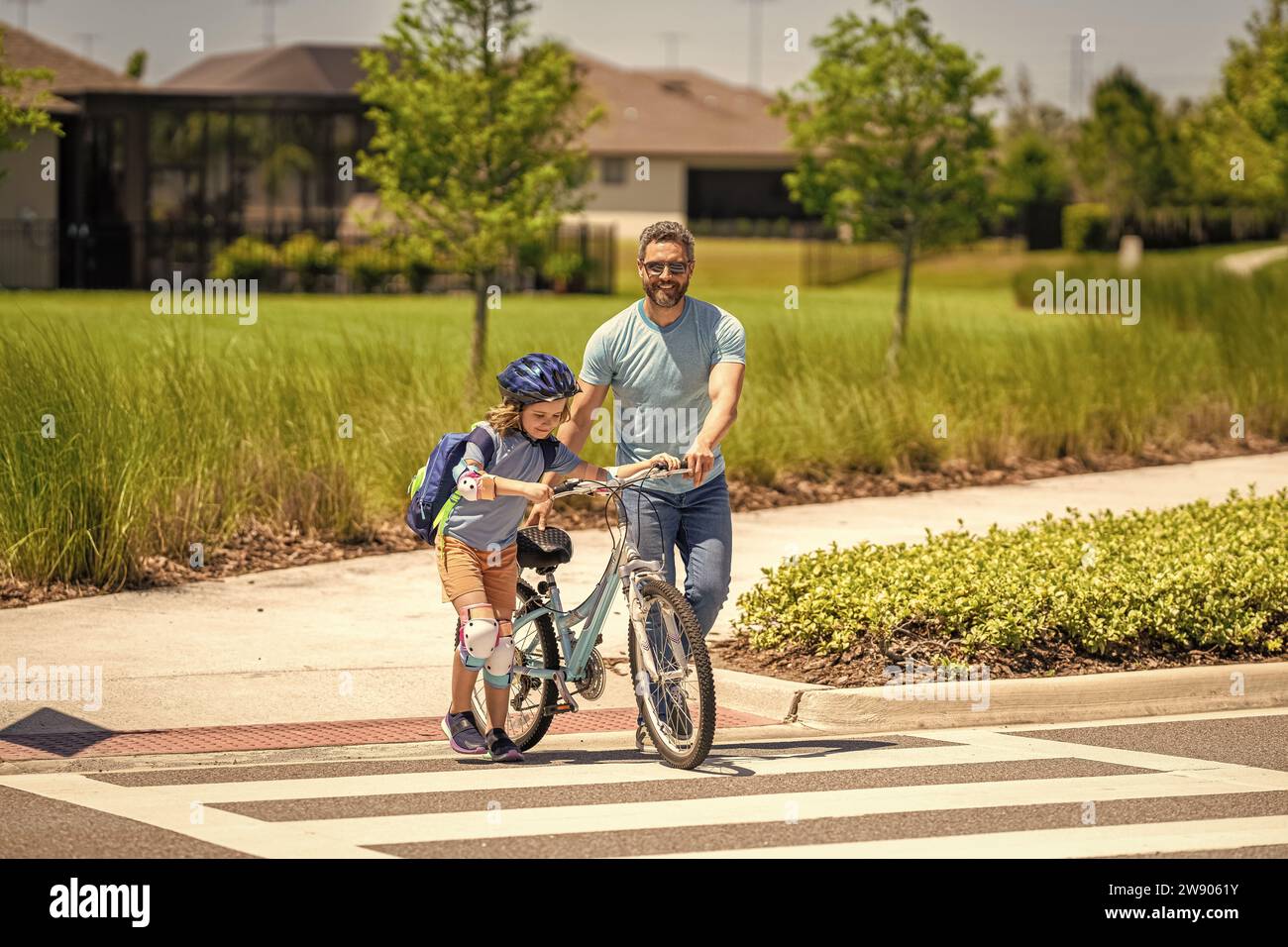 dad guiding his son first bike ride. dad and son enjoying fun bike ...