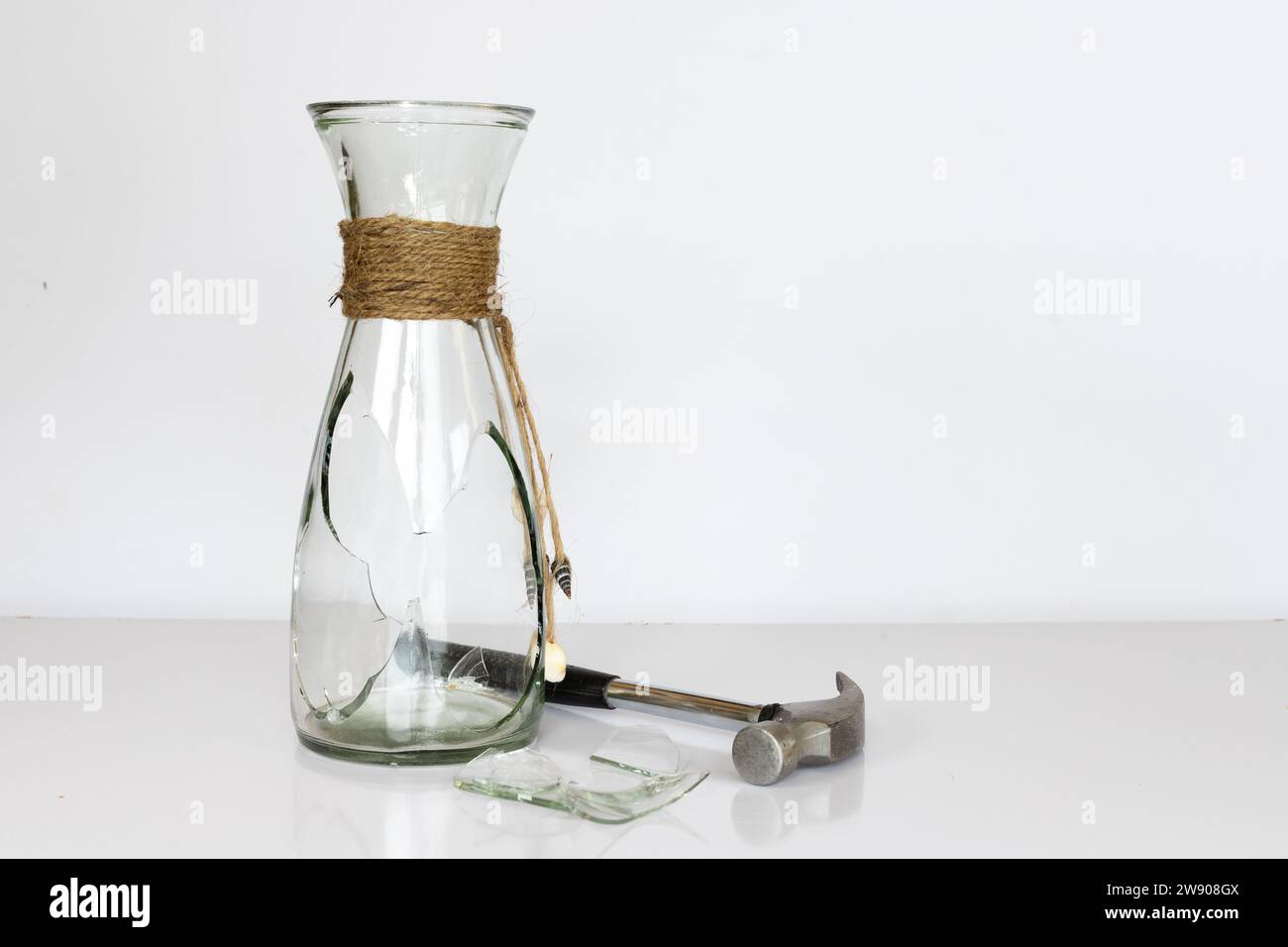 Broken transparent glass vase with hammer isolated on a white ...
