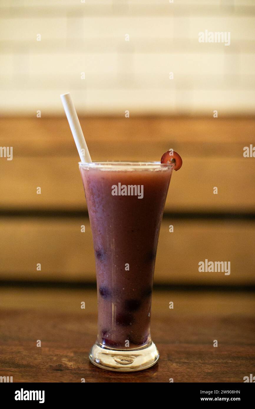 A close-up photo of a glass of purple liquid, likely grape juice, with ...
