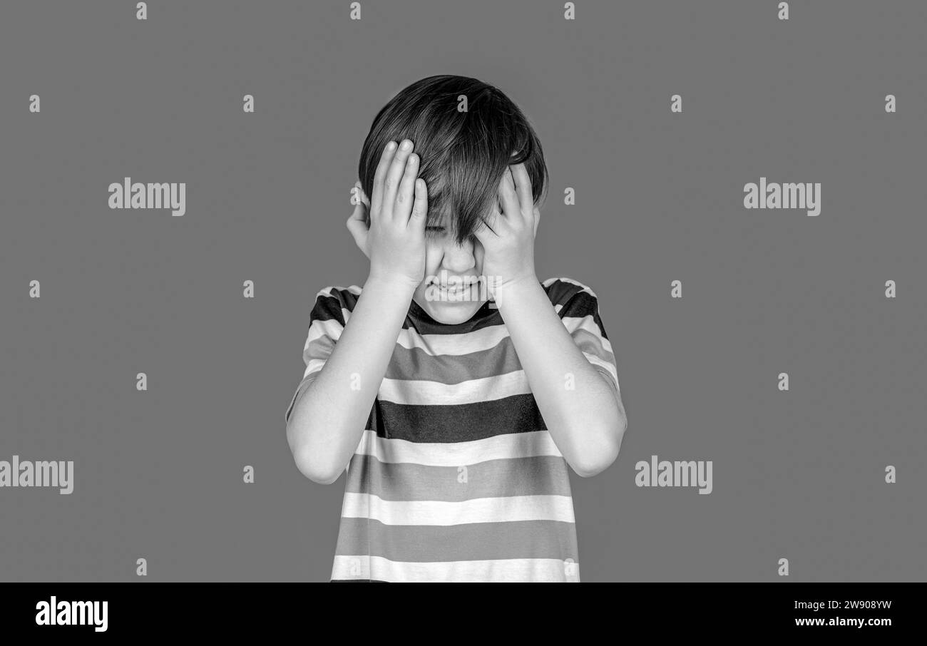 Headache child. Headache because stress. Portrait of a sad boy holding ...