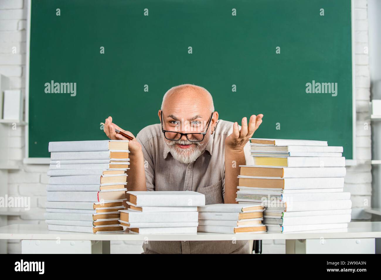 Teacher with books in school. Man elementary school teacher standing in ...