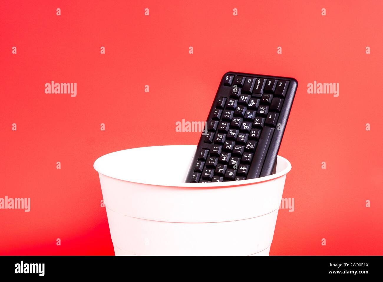 Woman putting a computer keyboard in the e-waste trash bin, recycling ...