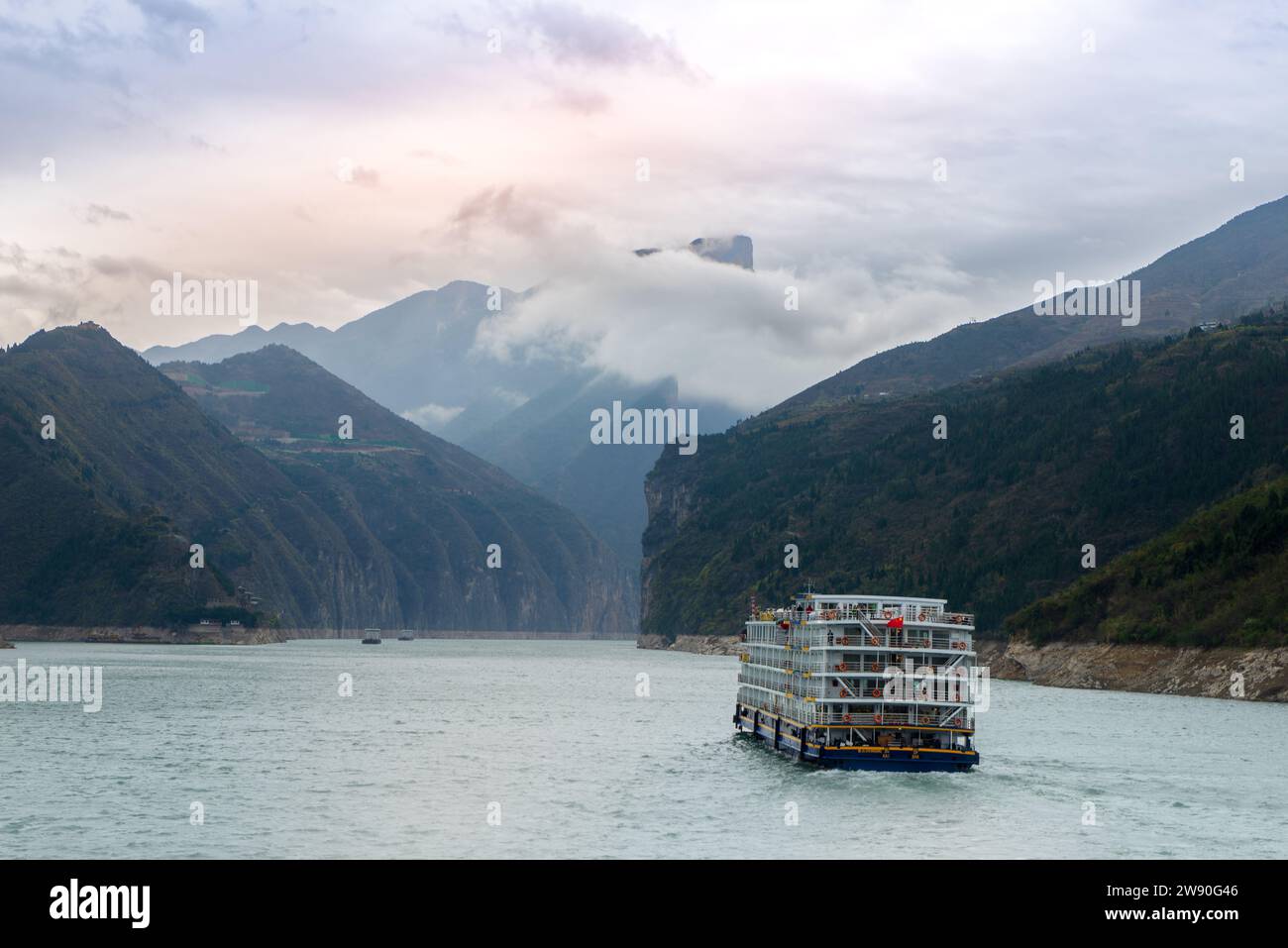 A lone boat traverses the tranquil waters of the Yangtze River, amidst ...